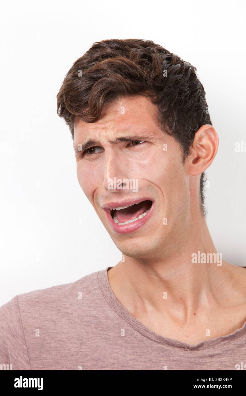 Frightened young man crying against white background Stock Photo - Alamy