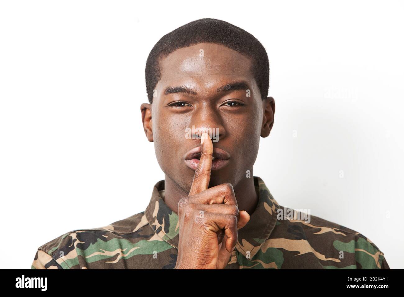 Portrait of young military soldier in camouflage clothing making silent ...
