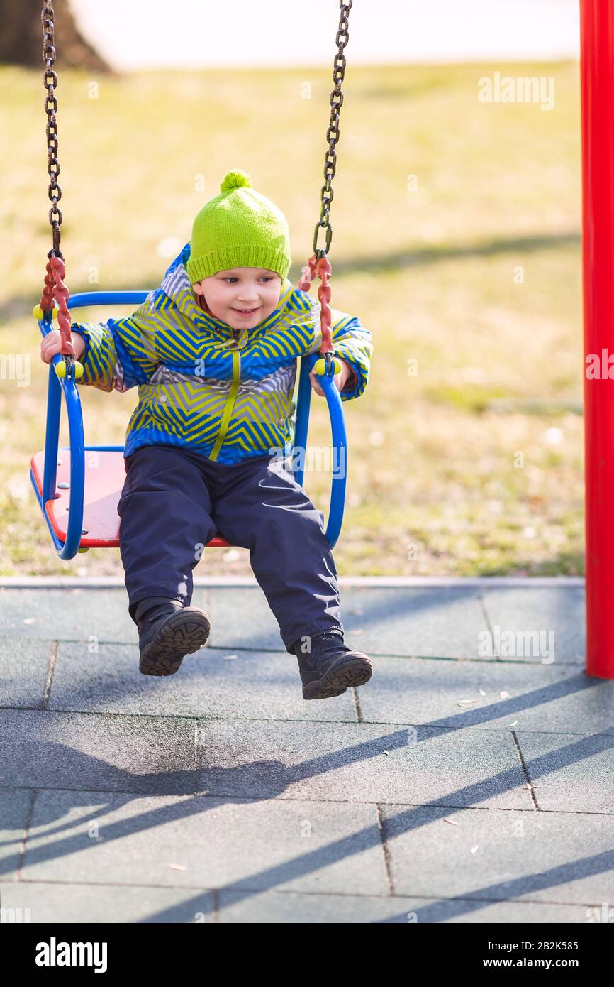 Happy little baby boy swinging on a swing on the playground outdoor ...