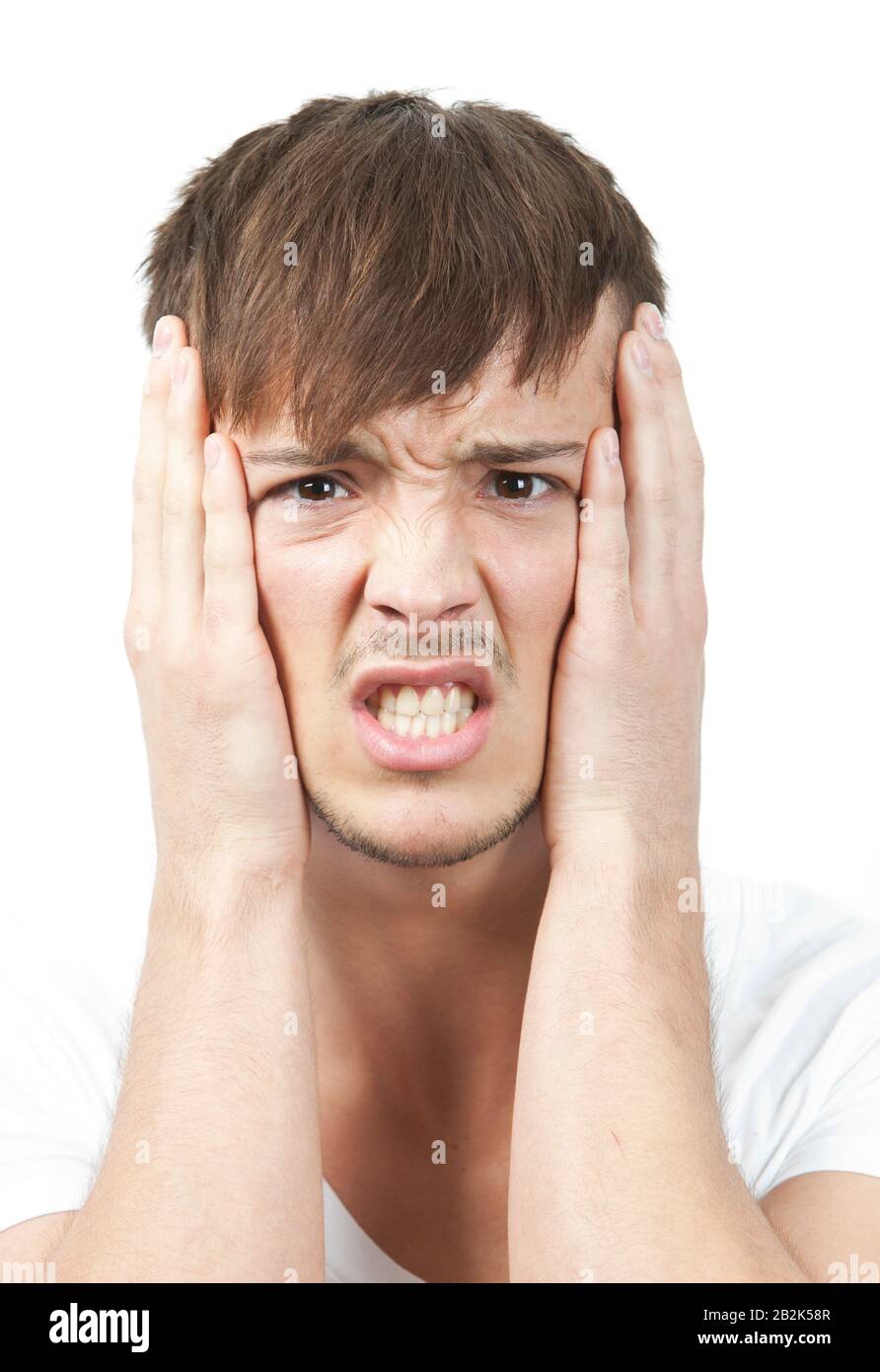 Portrait of frustrated young man clenching teeth against white ...