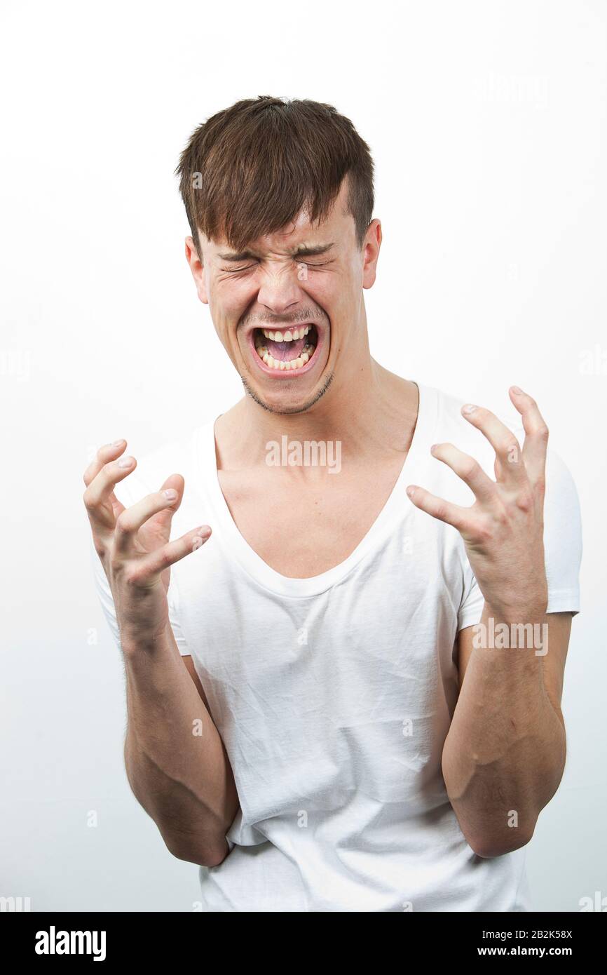 Aggressive young man screaming against white background Stock Photo - Alamy