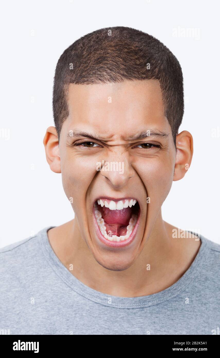 Portrait of aggressive young mixed race man screaming against white ...