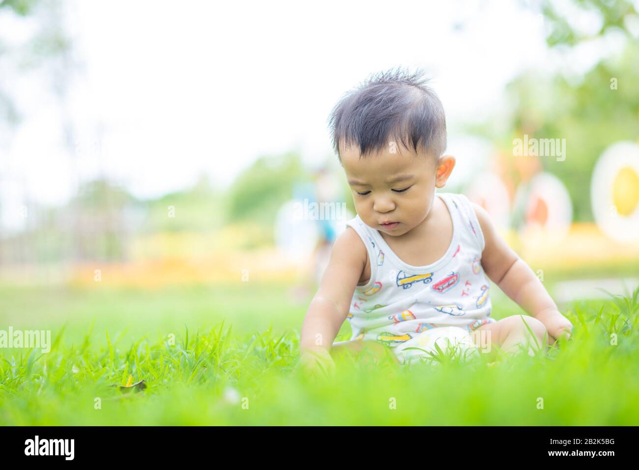 Adorable little boy sitting in green park field playing on meadow Stock ...