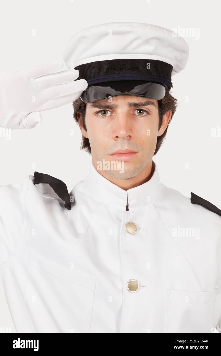 Portrait of young navy officer saluting against gray background Stock ...