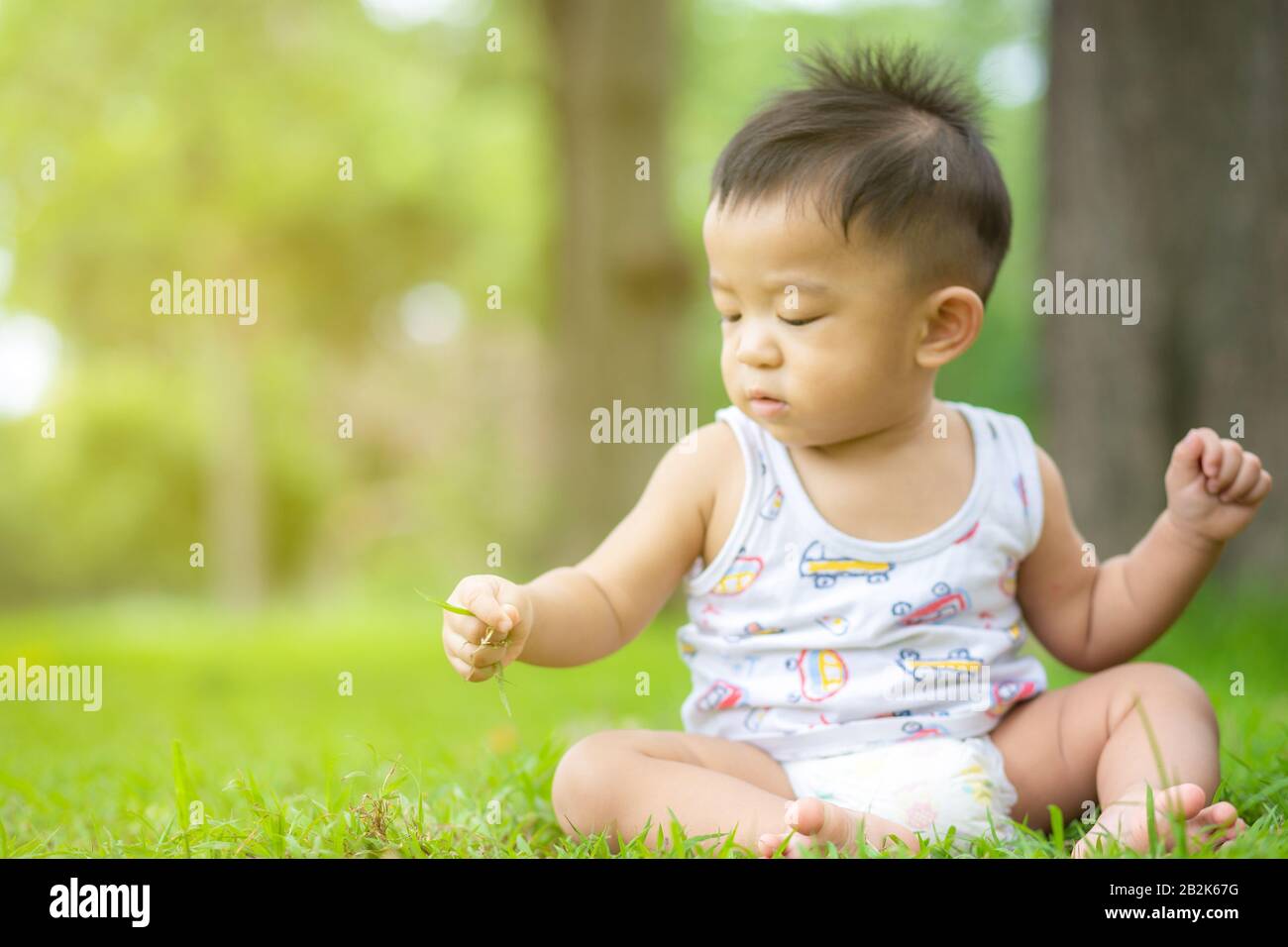 Adorable little boy sitting in green park field playing on meadow Stock ...