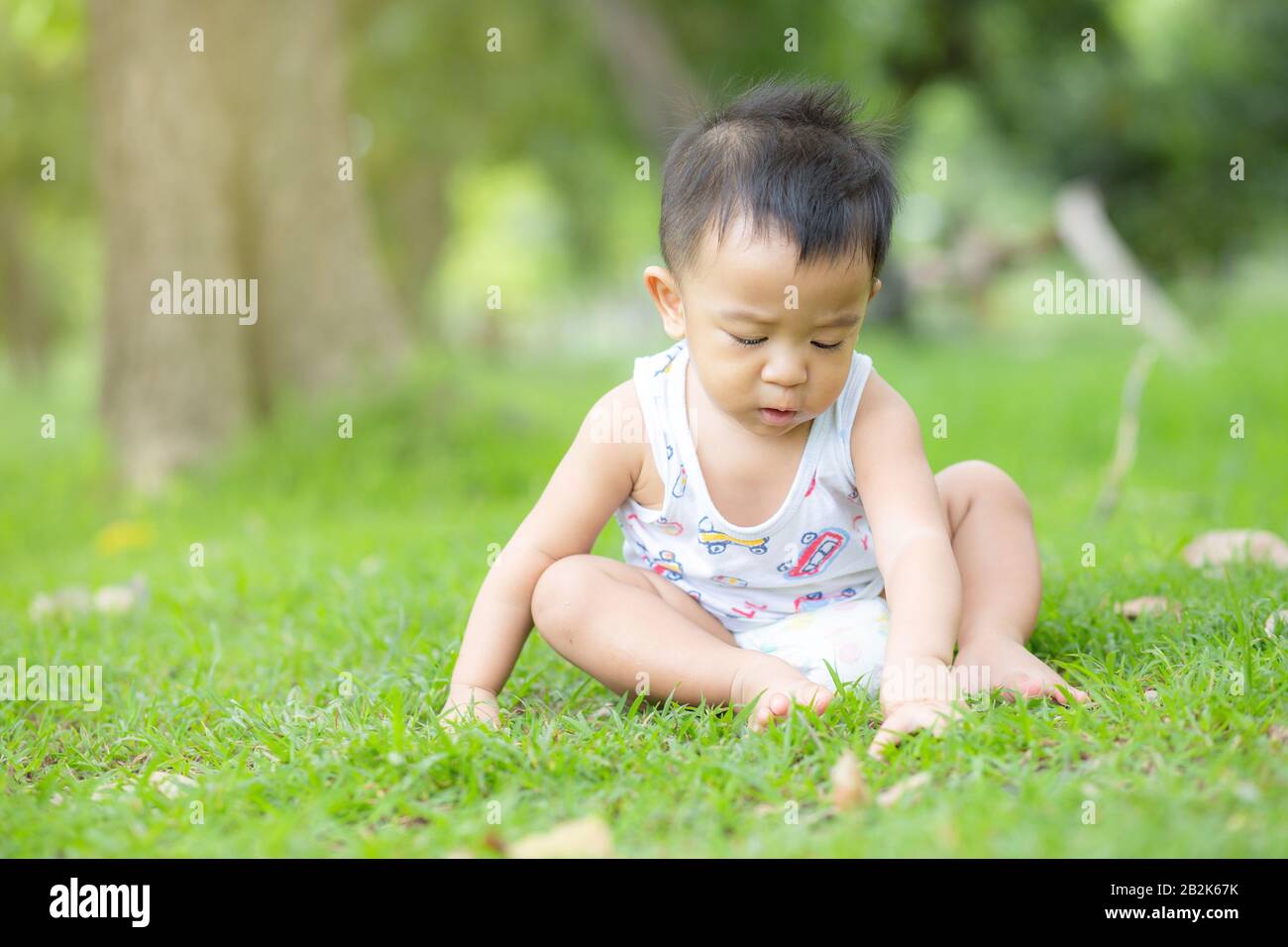Adorable little boy sitting in green park field playing on meadow Stock ...