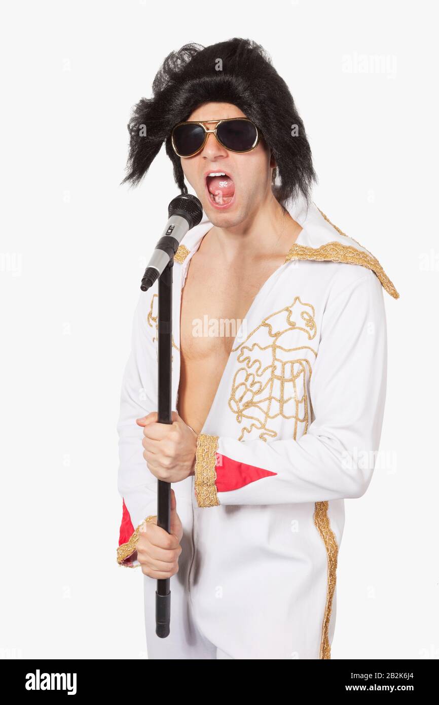 Elvis impersonator singing into a microphone against gray background ...