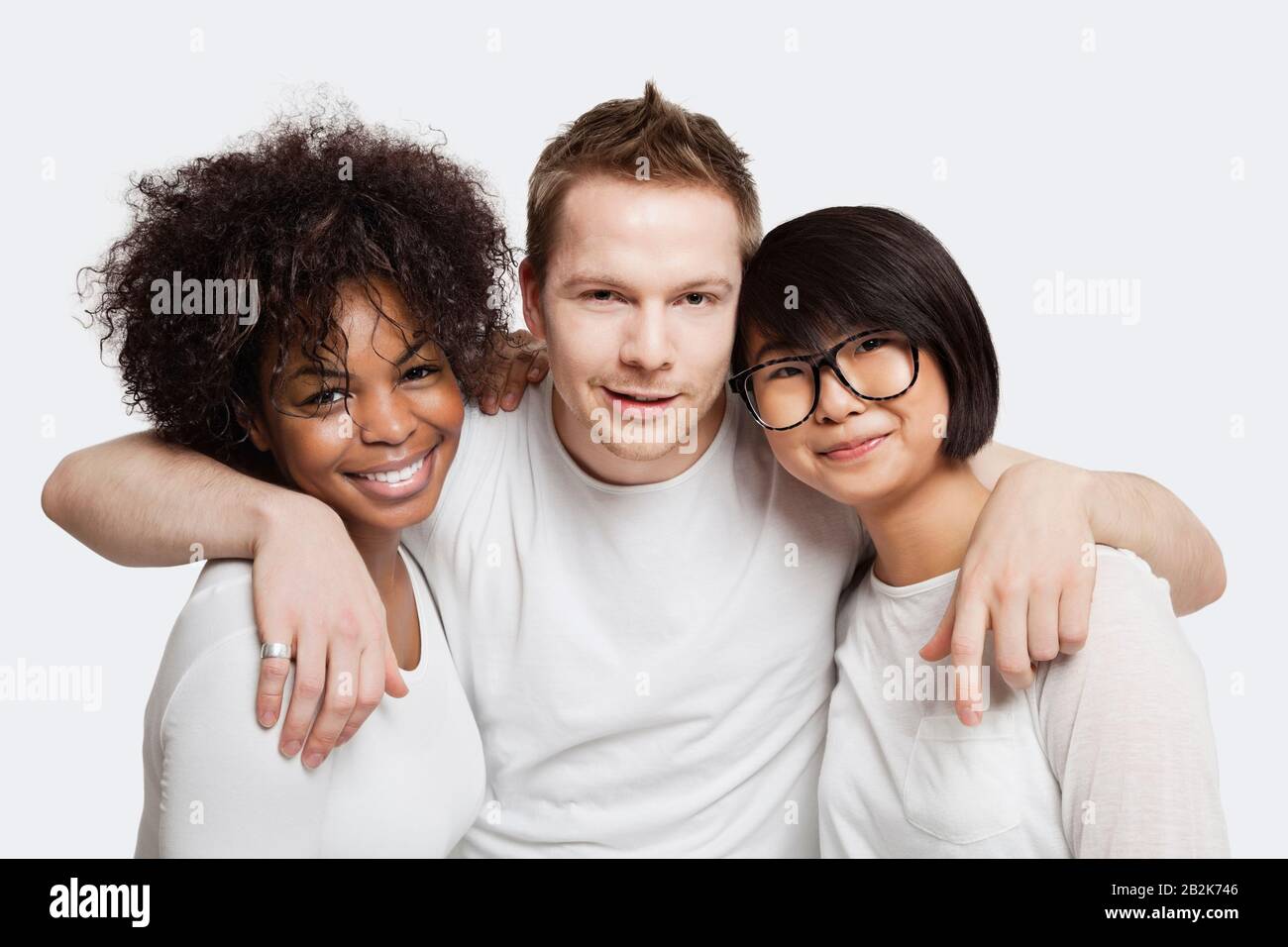 Portrait of young Caucasian man with his arms around two female friends ...