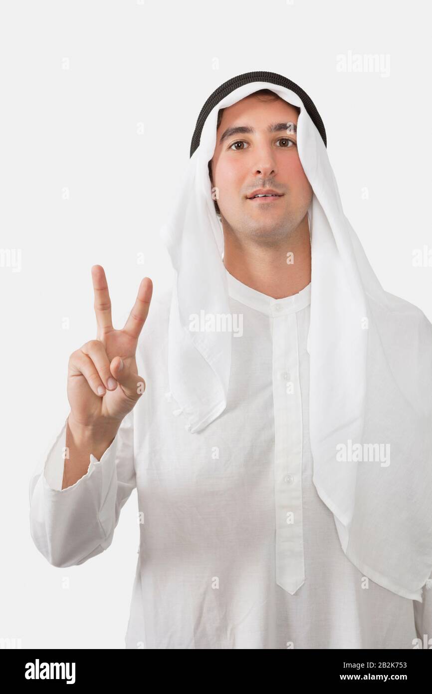 Arab man gesturing V-sign over white background Stock Photo - Alamy