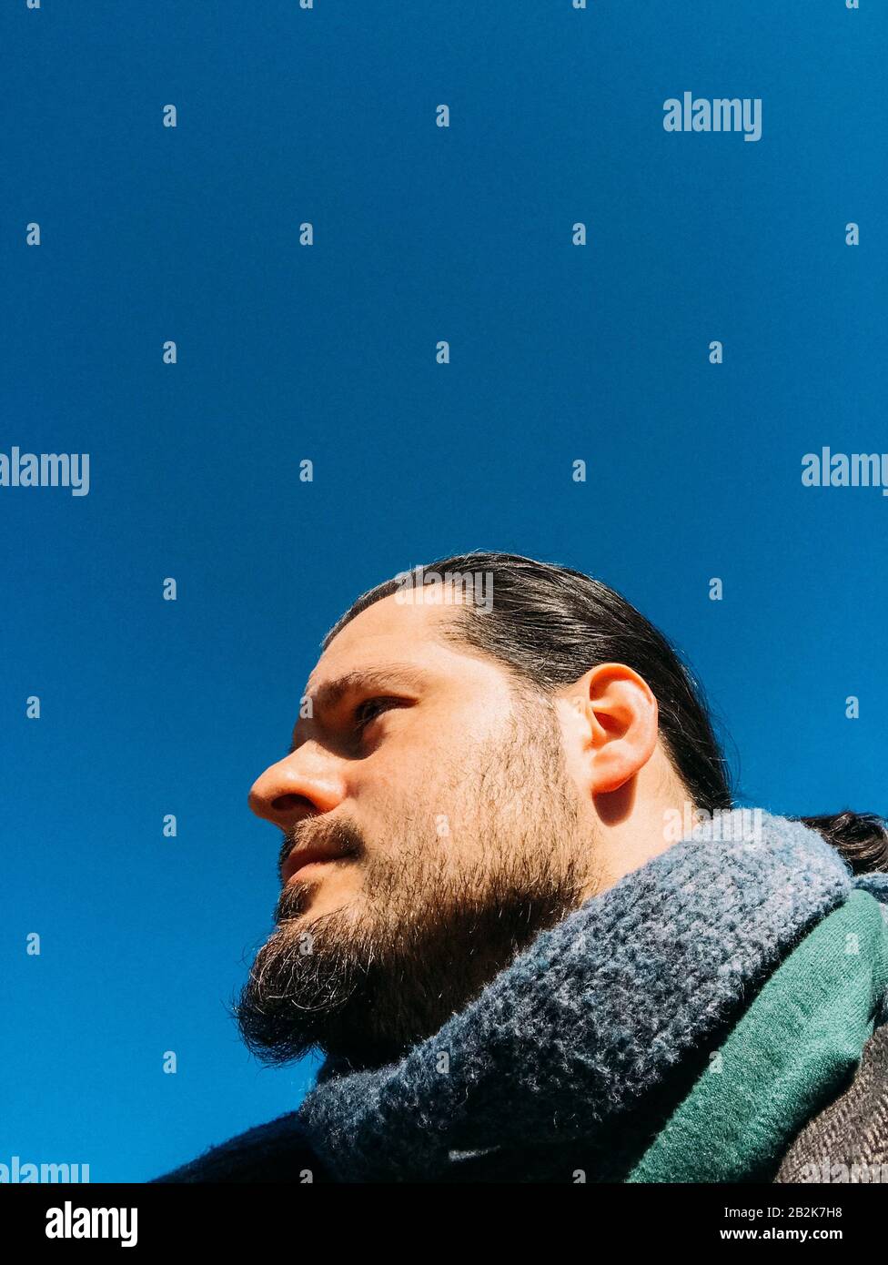Bearded hipster man with long hair portrait. Perspective from below ...