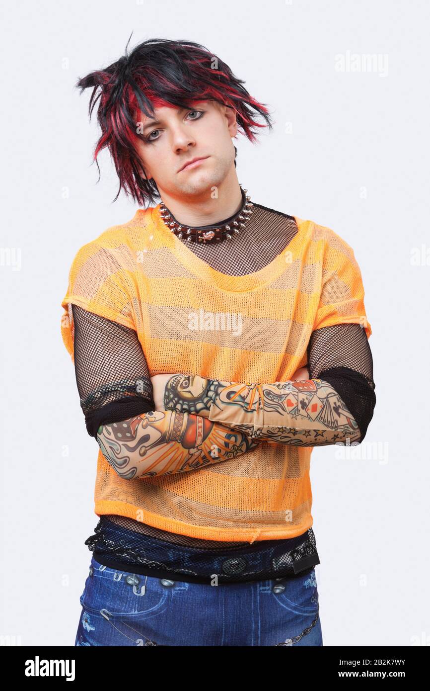 Portrait of young punk man standing with arms crossed over white ...