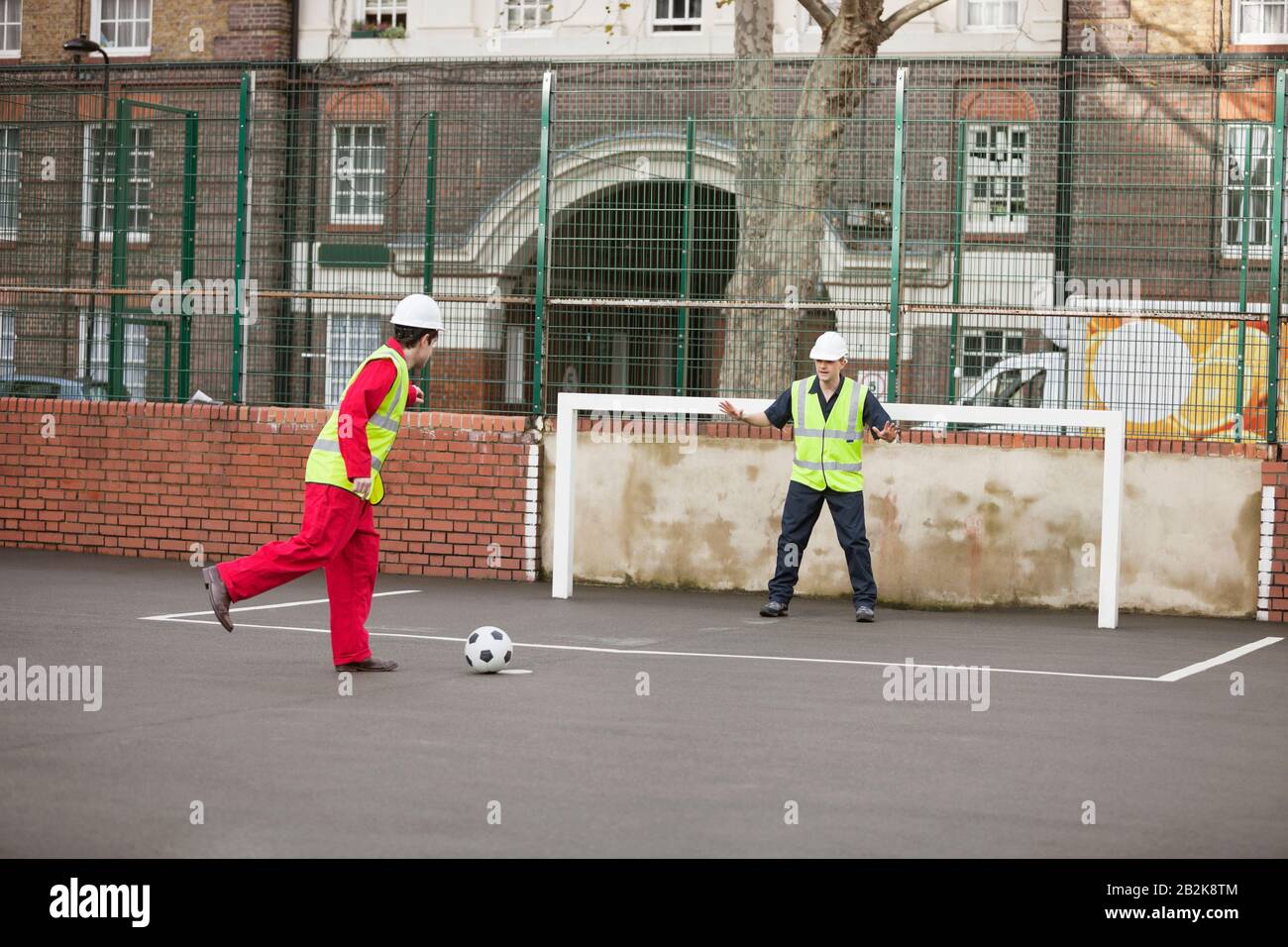 Two manual workers playing football Stock Photo - Alamy