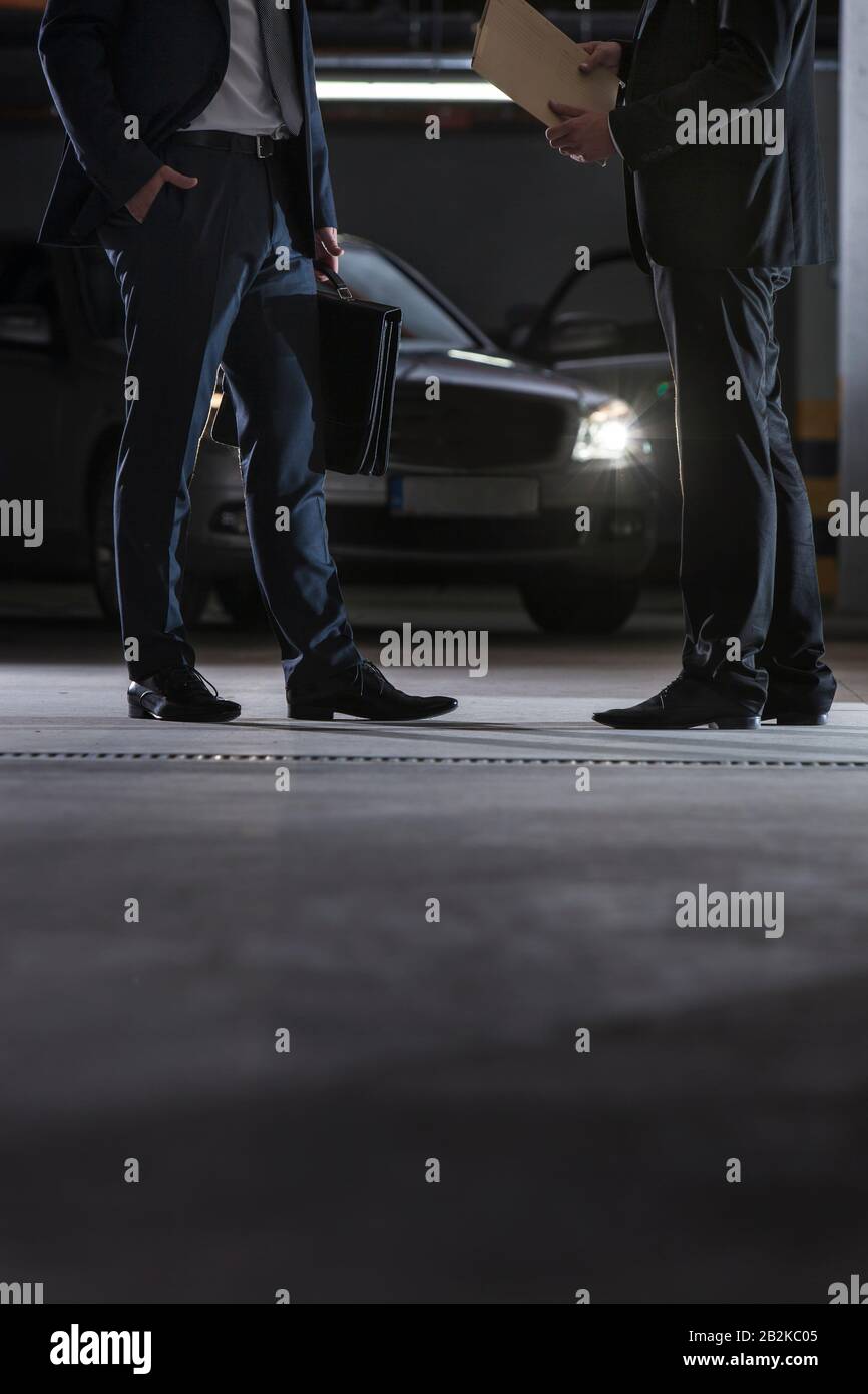 Low section of businessmen conducting suspicious business in basement ...