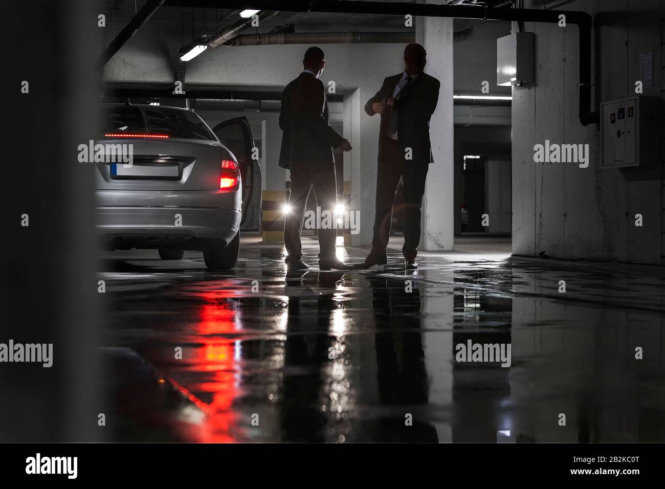 Full length of businessmen conducting suspicious business in parking ...