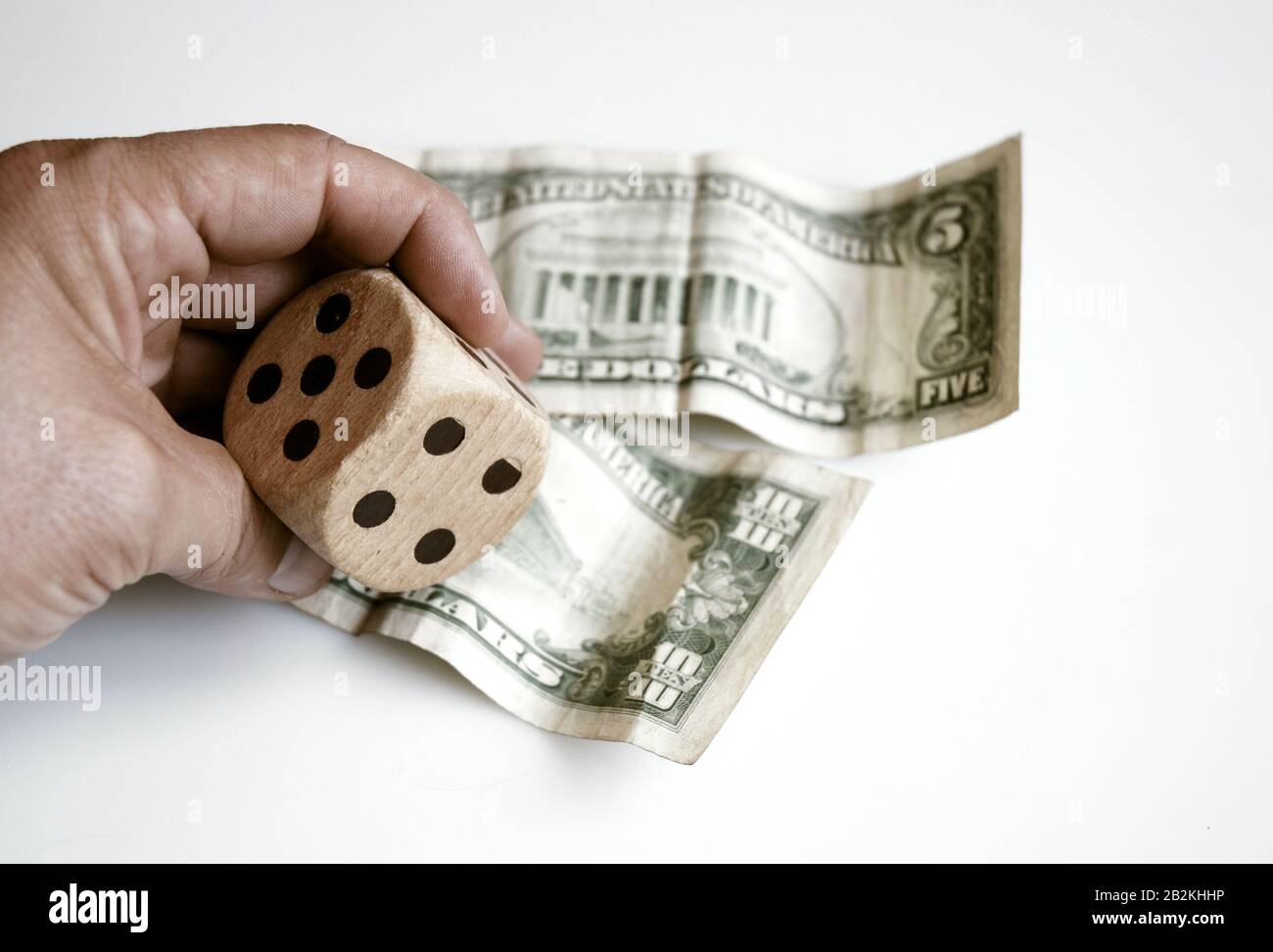 Banknotes and a hand holding a wooden cube symbol picture of gamble ...