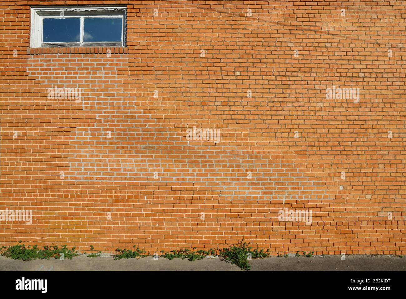 a red and orange brick wall building with a single small window Stock ...