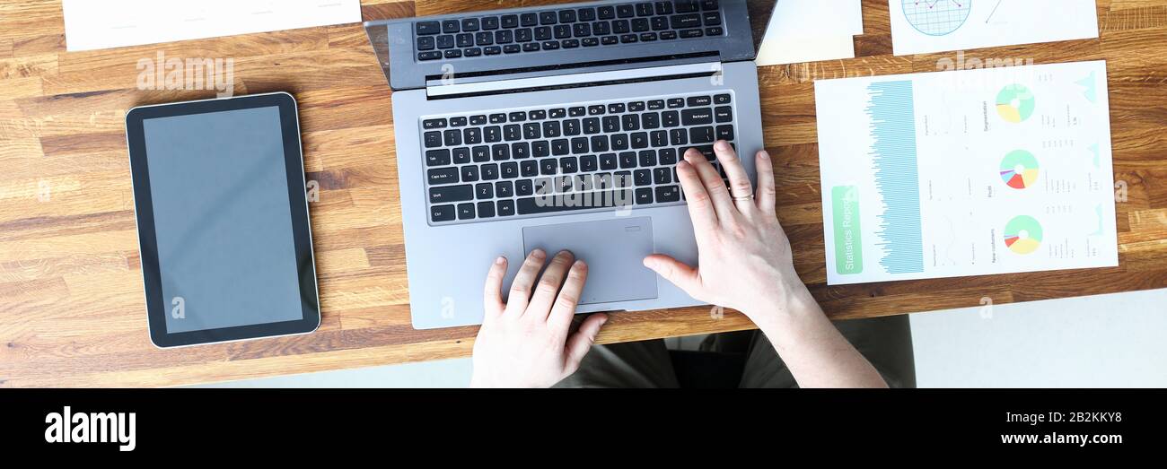 Man in office enters data from report into laptop Stock Photo - Alamy