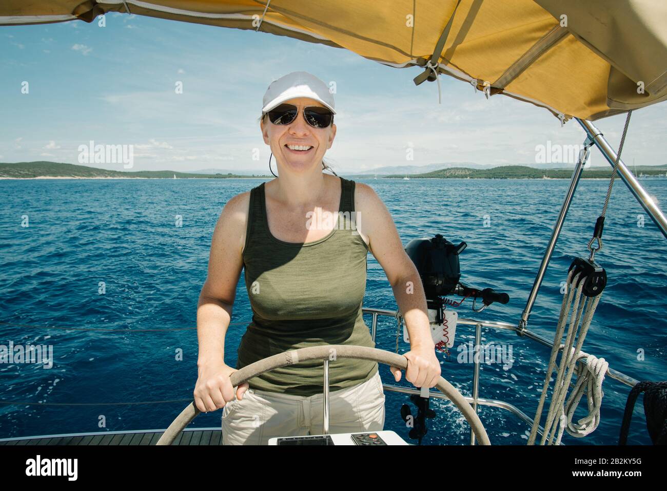 Female skipper on the steering wheel of a yacht. Sailing and yachting ...