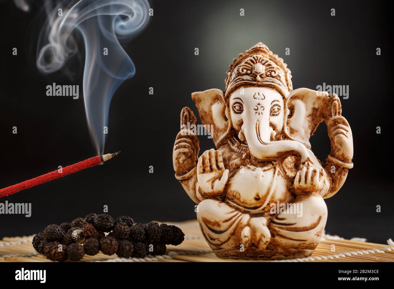 Ganesha on a black background. Statue and rosary with red smoldering ...