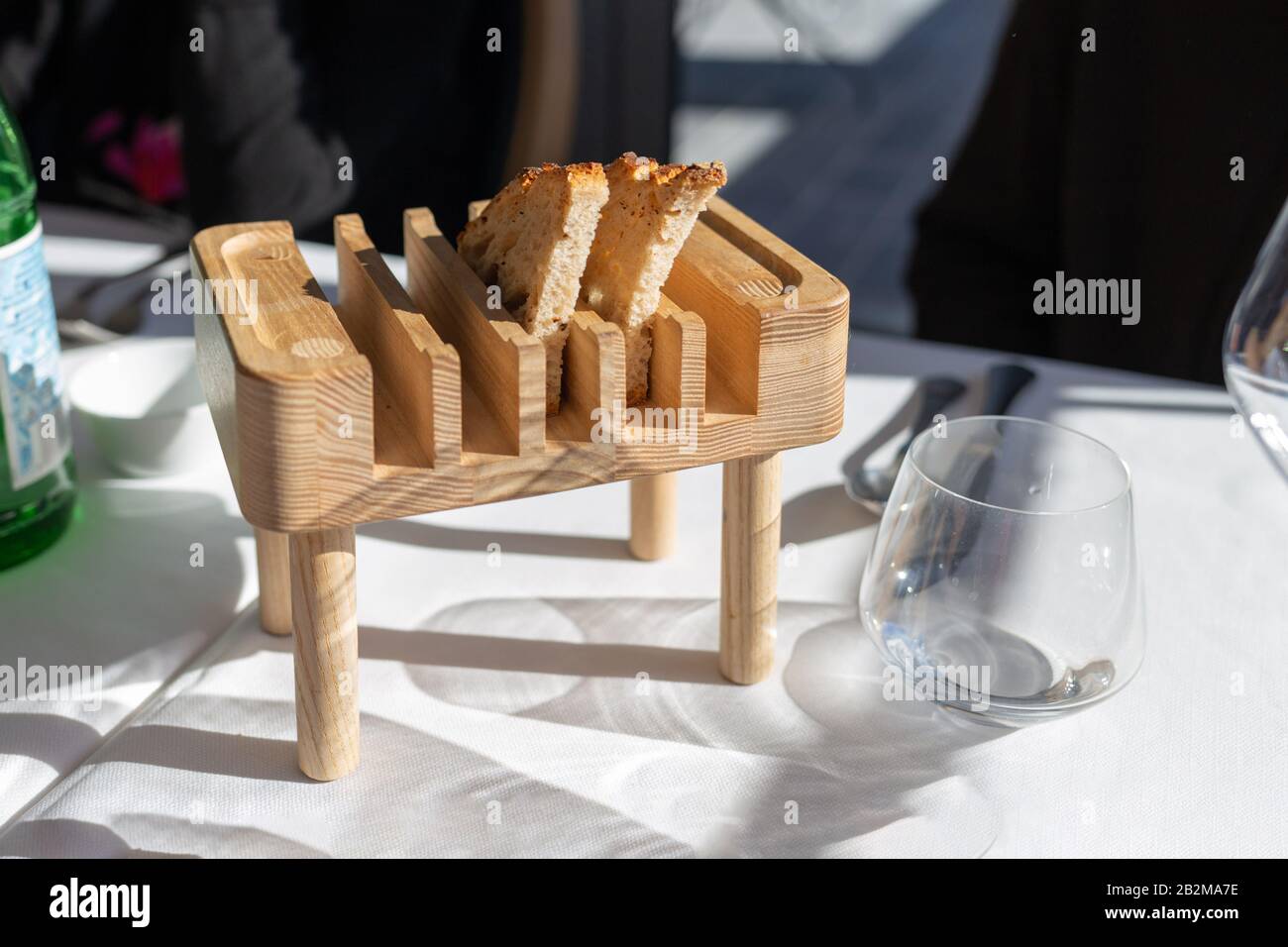 Close up of fresh slice crusty bread in a restaurant, wooden stand for ...