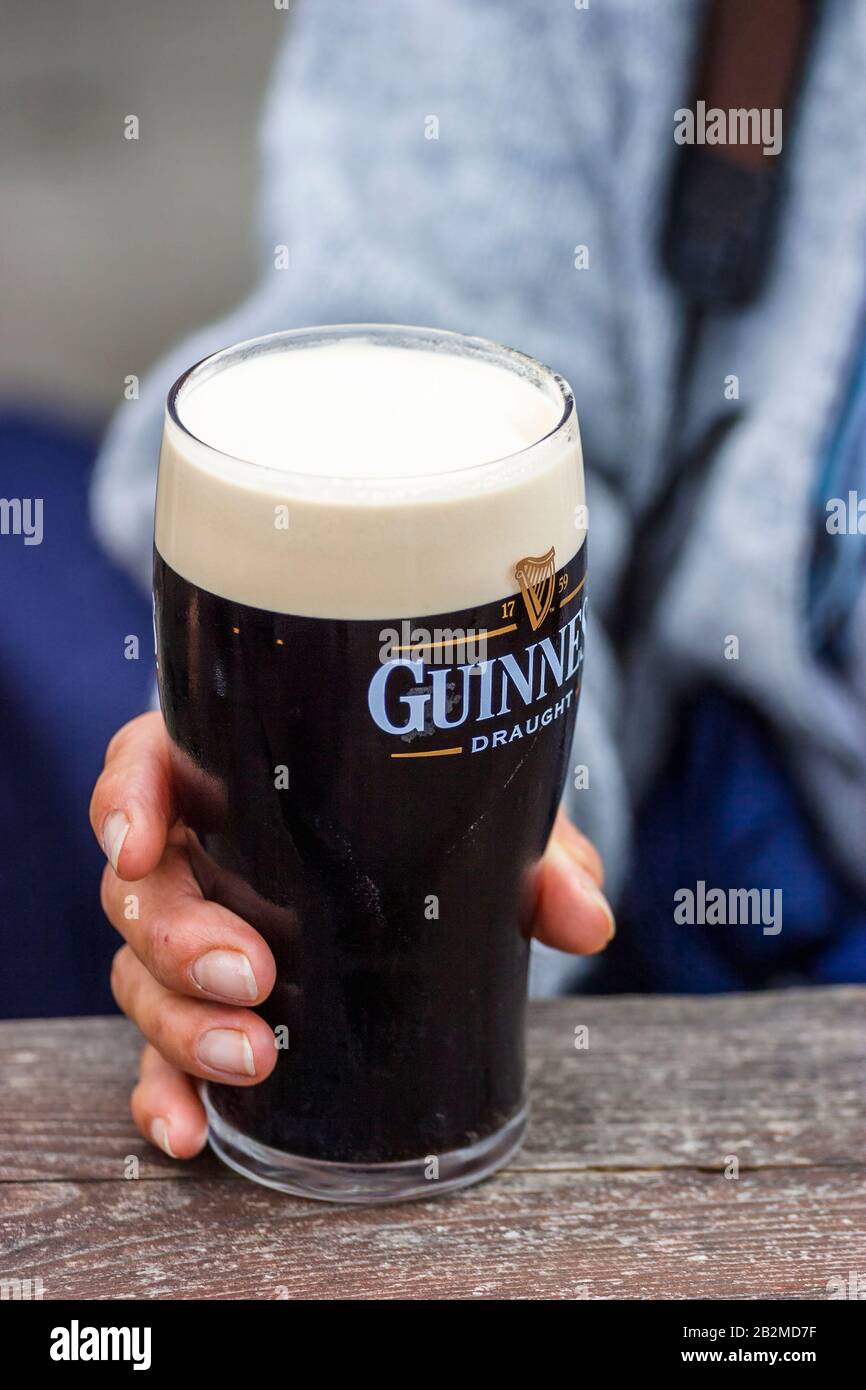 Woman holding a pint of guinness at an outdoors restaurant Stock Photo ...
