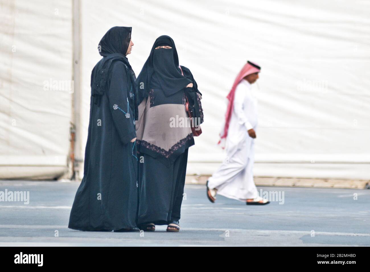 Muslim women wearing black burka and muslim man in the background. Souq ...