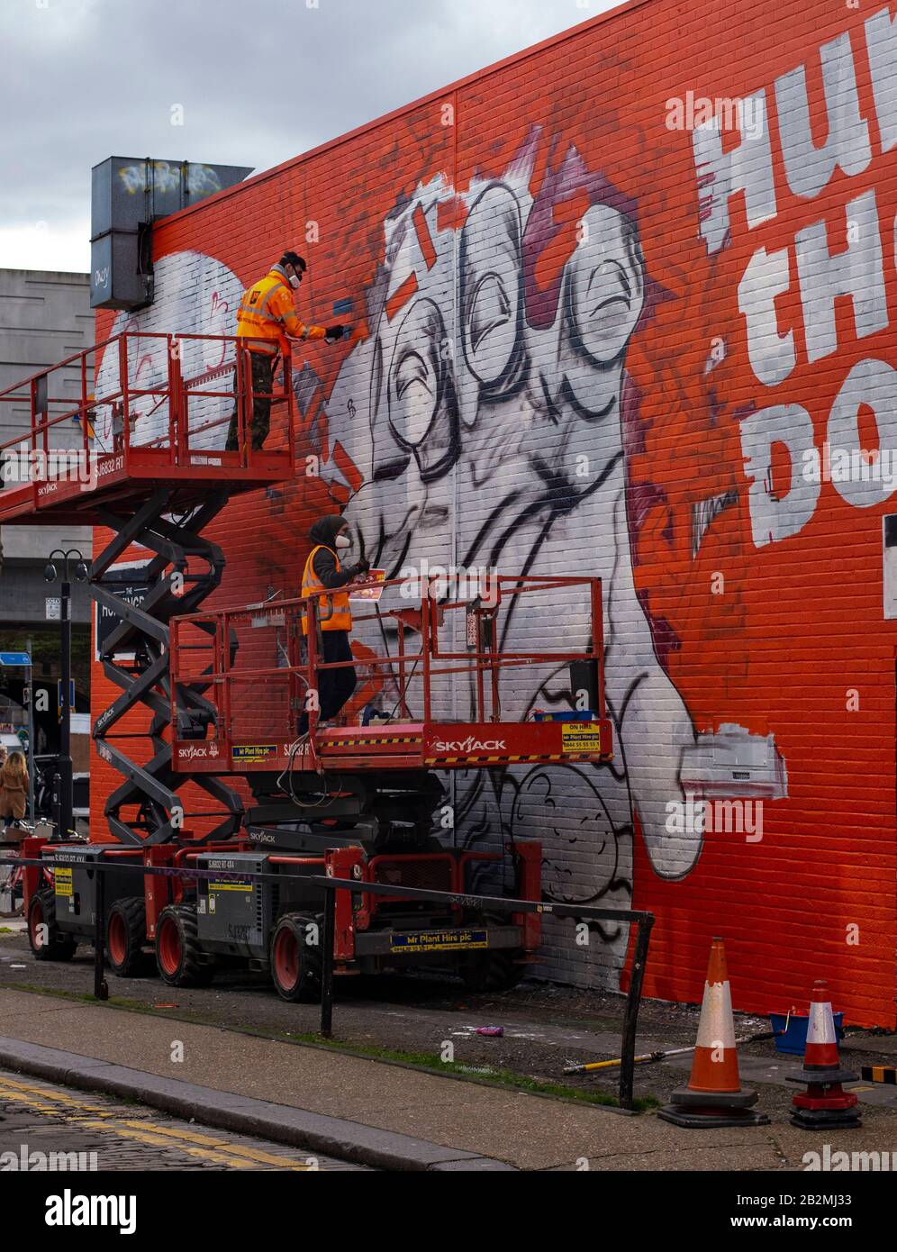 Two graffiti artists work at a huge piece of street art wearing hi ...
