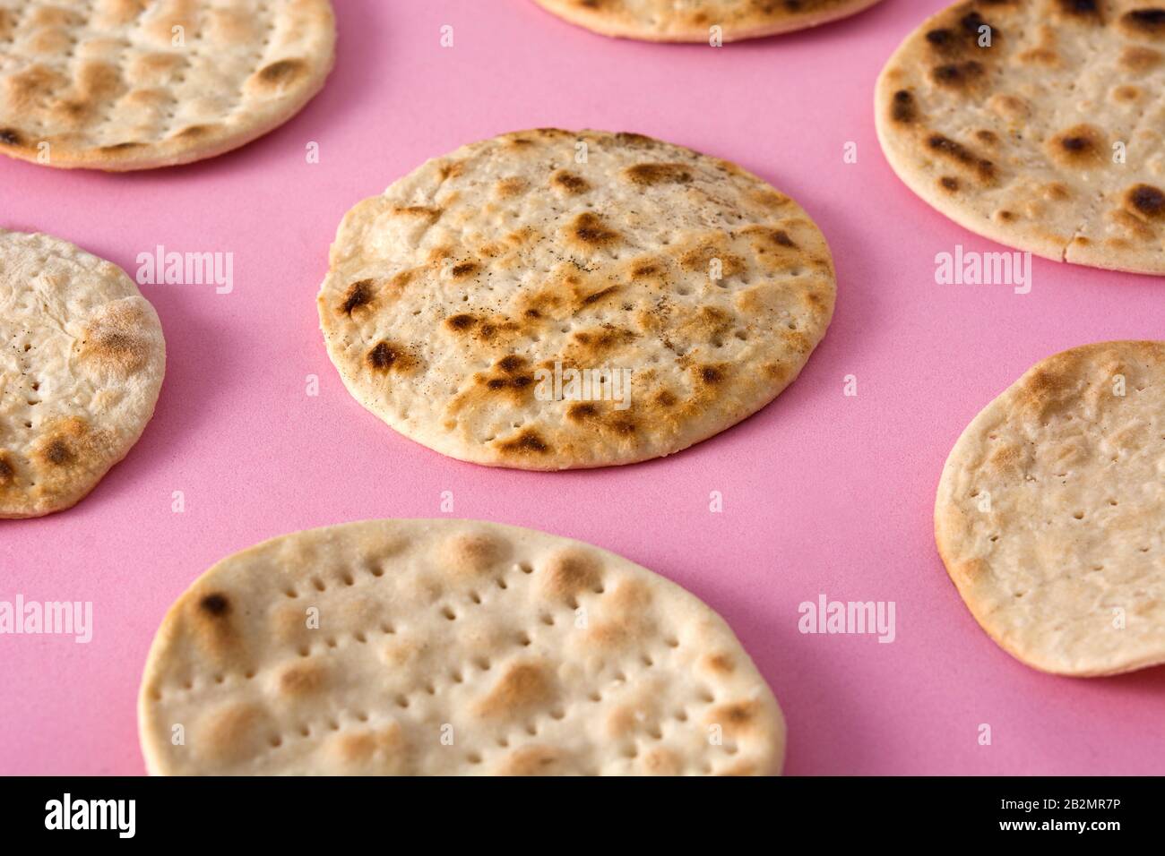 Handmade matzah for Jewish Passover on pink background Stock Photo - Alamy