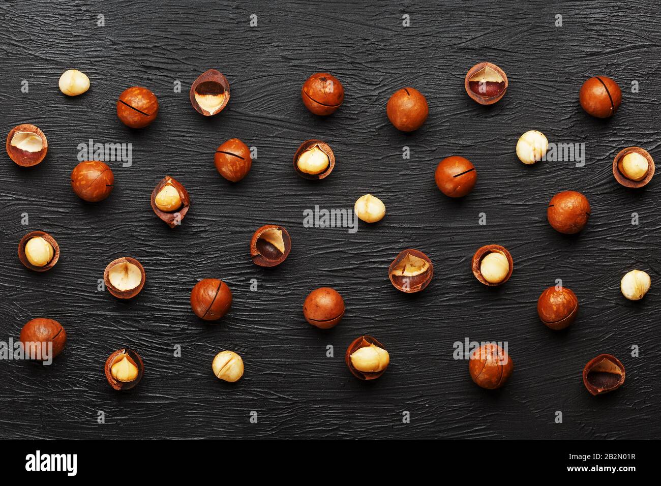 Purified and shell repeats macadamia nuts on black textural stone ...