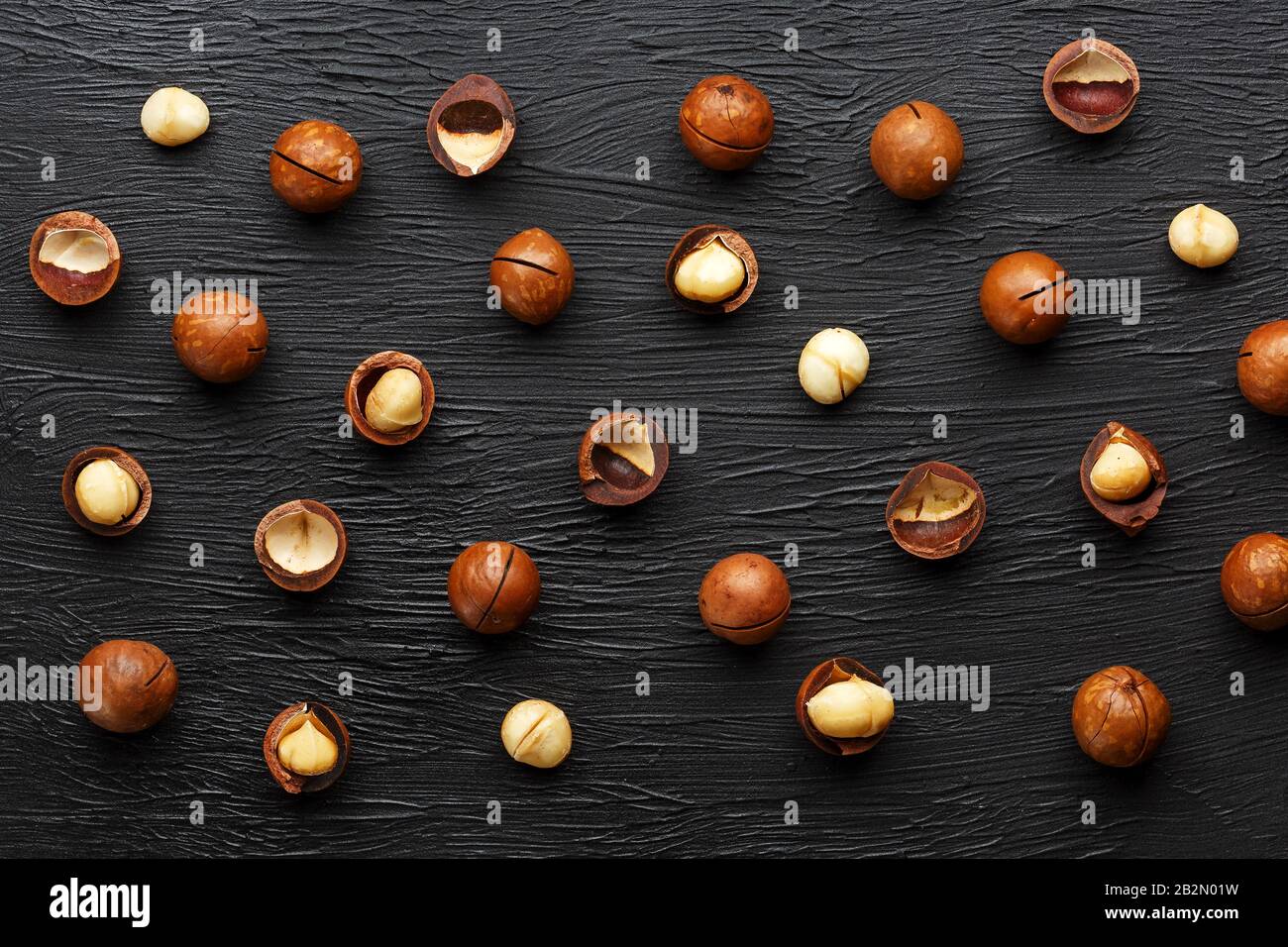 Purified and shell repeats macadamia nuts on black textural stone ...