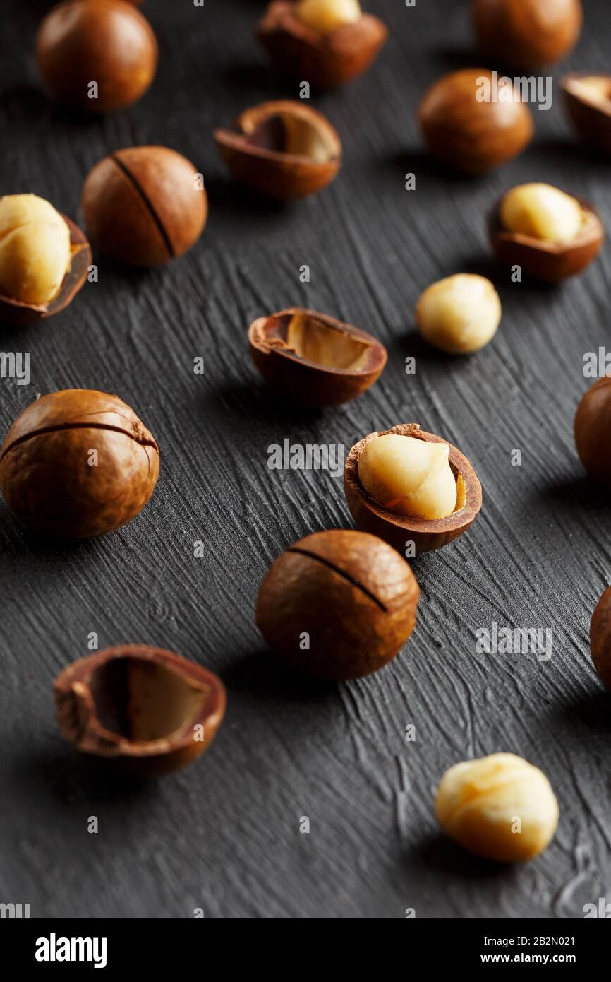 Purified and shell repeats macadamia nuts on black textural stone ...