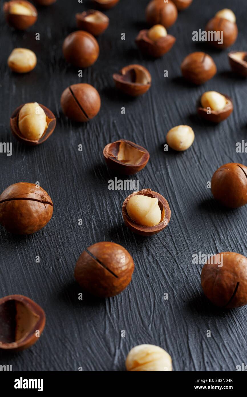 Purified and shell repeats macadamia nuts on black textural stone ...