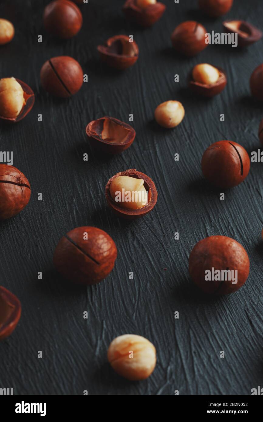 Purified and shell repeats macadamia nuts on black textural stone ...
