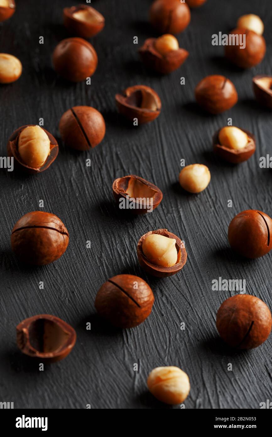 Purified and shell repeats macadamia nuts on black textural stone ...