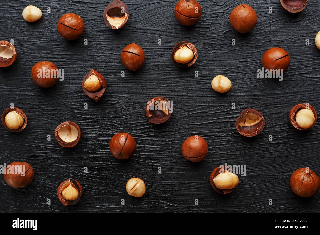 Purified and shell repeats macadamia nuts on black textural stone ...