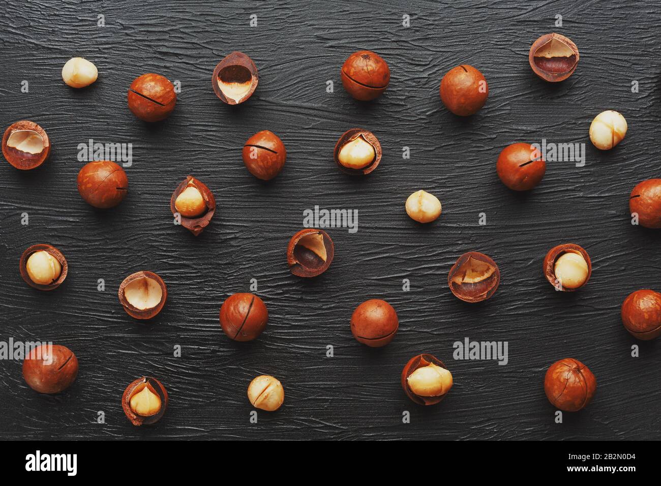 Purified and shell repeats macadamia nuts on black textural stone ...