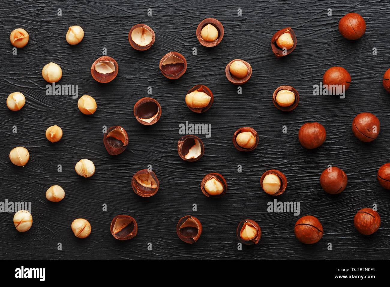 Purified and shell repeats macadamia nuts on black textural stone ...
