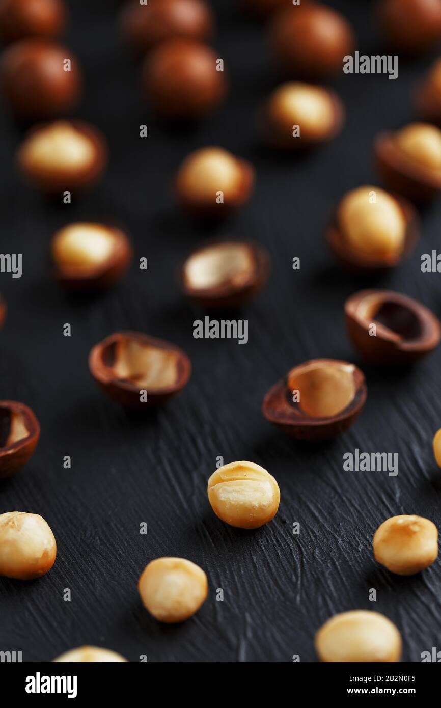 Purified and shell repeats macadamia nuts on black textural stone ...