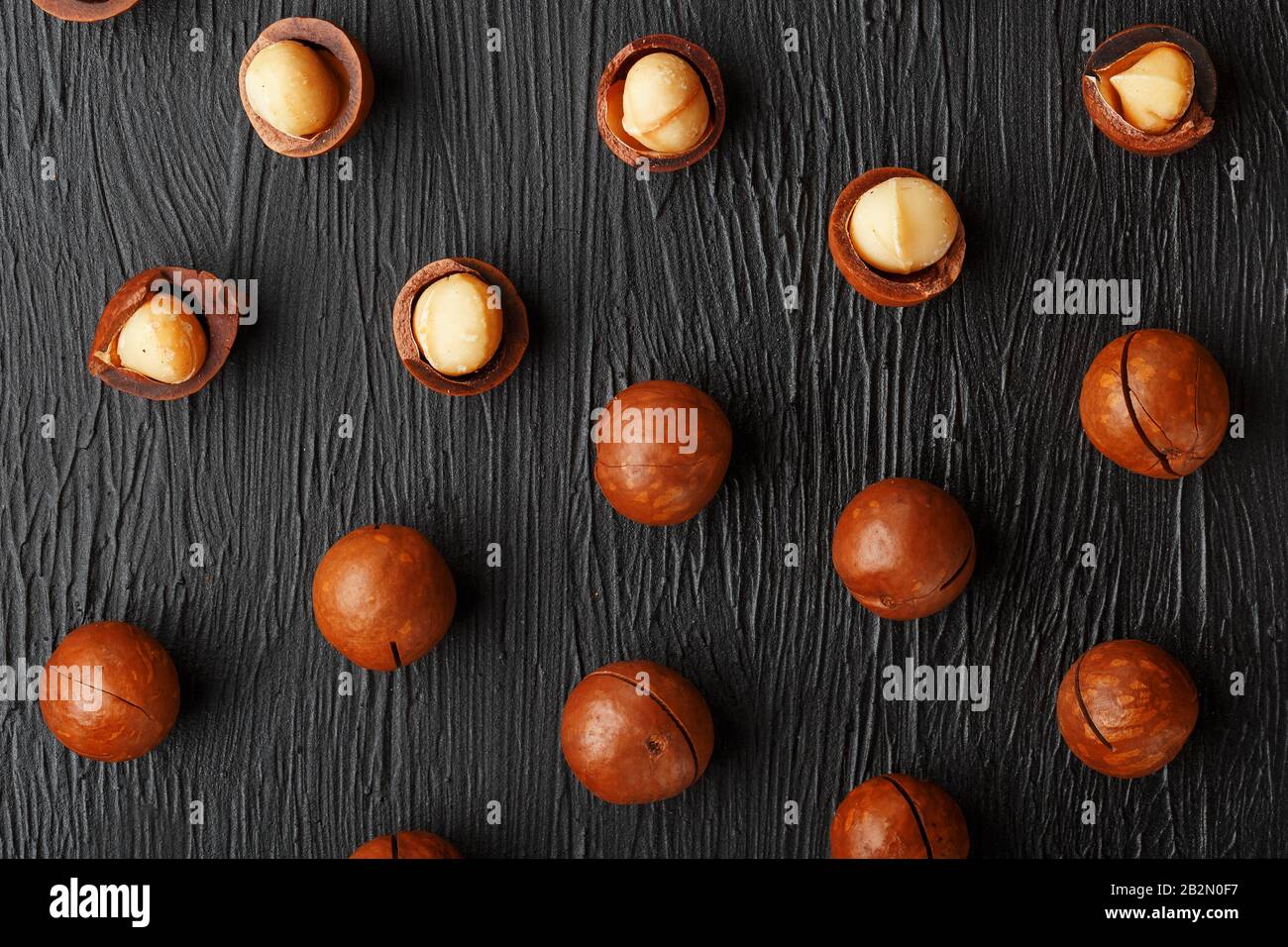 Purified and shell repeats macadamia nuts on black textural stone ...