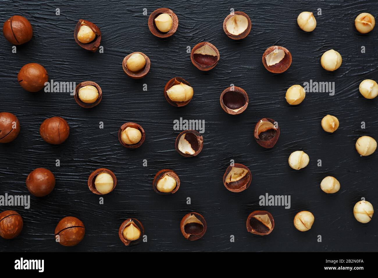 Purified and shell repeats macadamia nuts on black textural stone ...