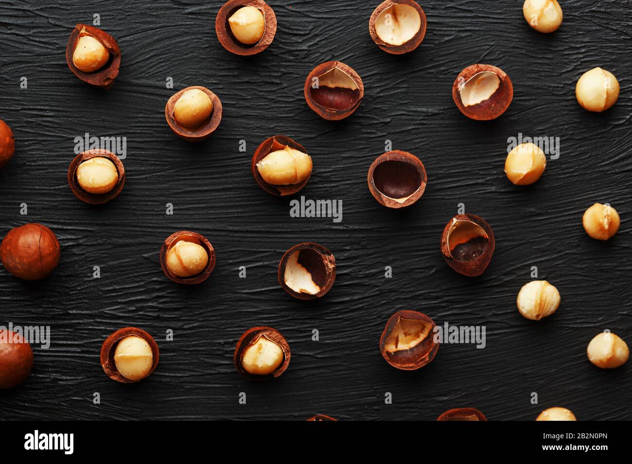 Purified and shell repeats macadamia nuts on black textural stone ...