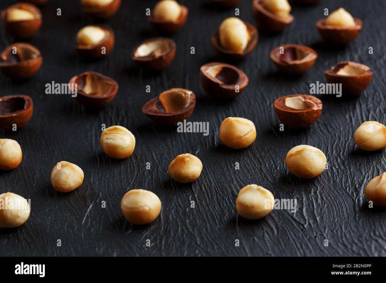 Purified and shell repeats macadamia nuts on black textural stone ...