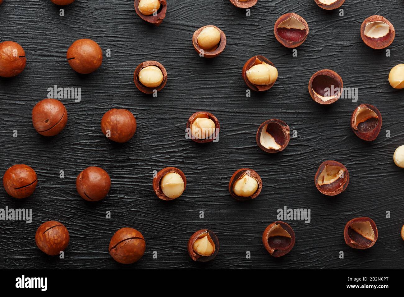 Purified and shell repeats macadamia nuts on black textural stone ...