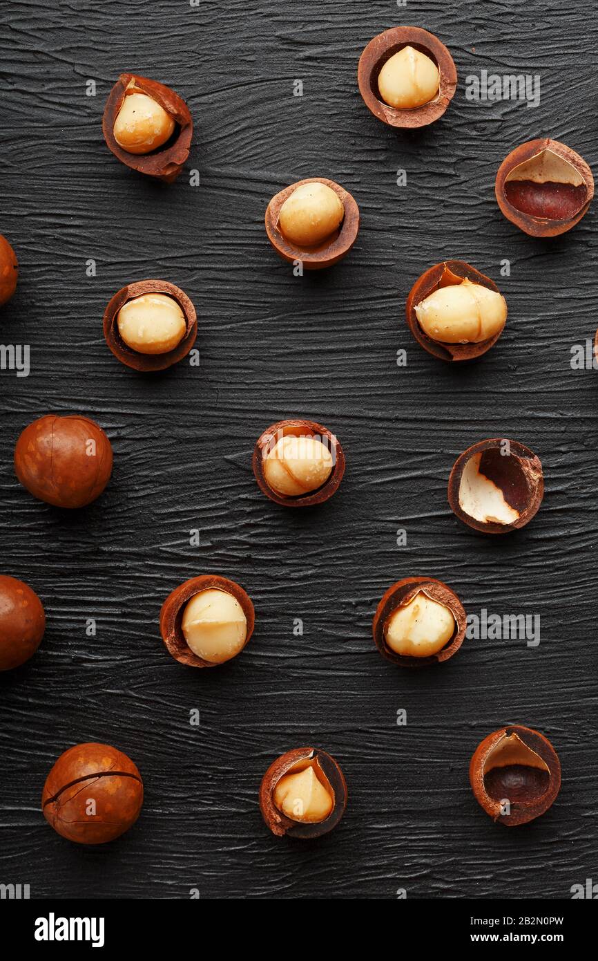 Purified and shell repeats macadamia nuts on black textural stone ...