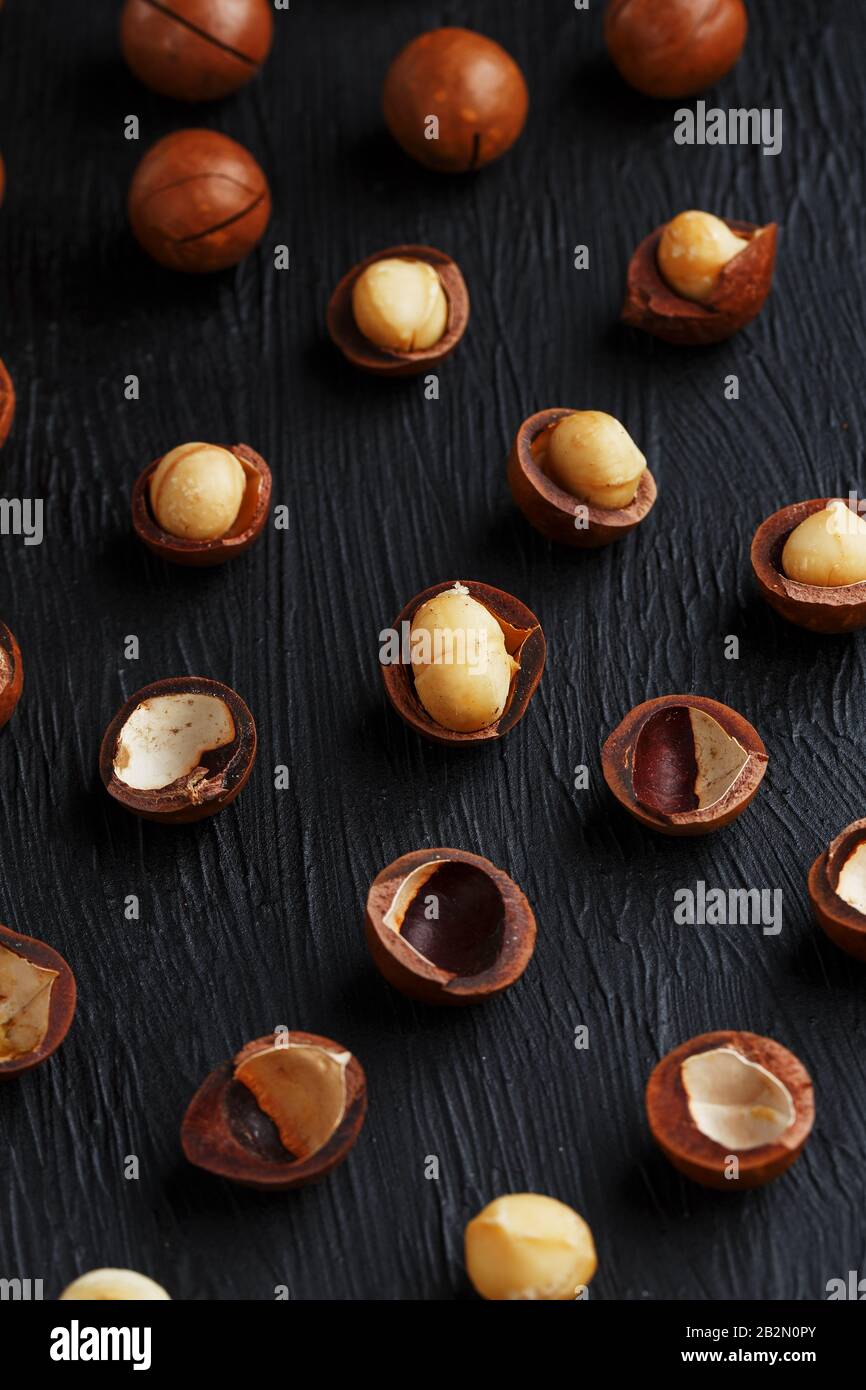 Purified and shell repeats macadamia nuts on black textural stone ...