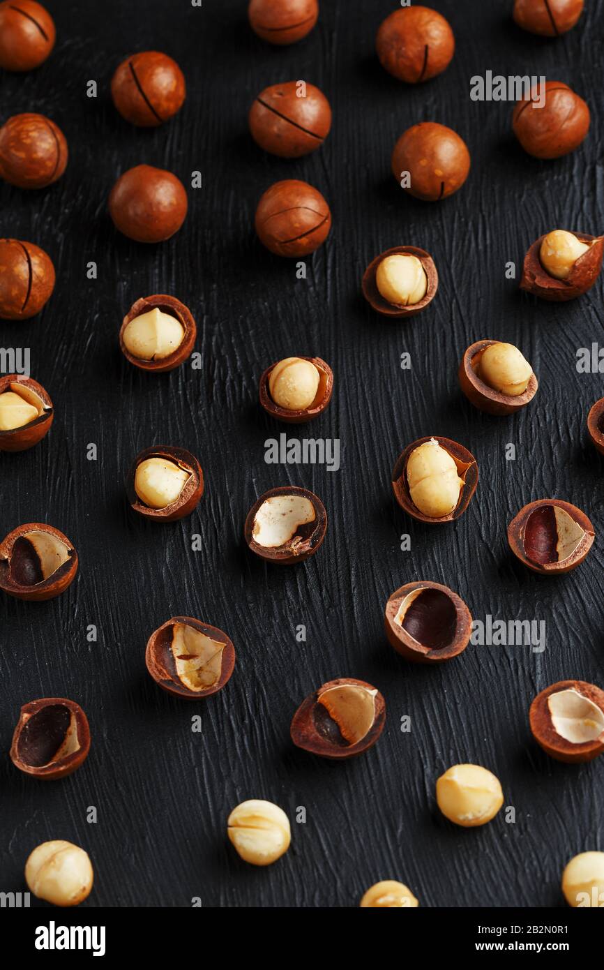 Purified and shell repeats macadamia nuts on black textural stone ...