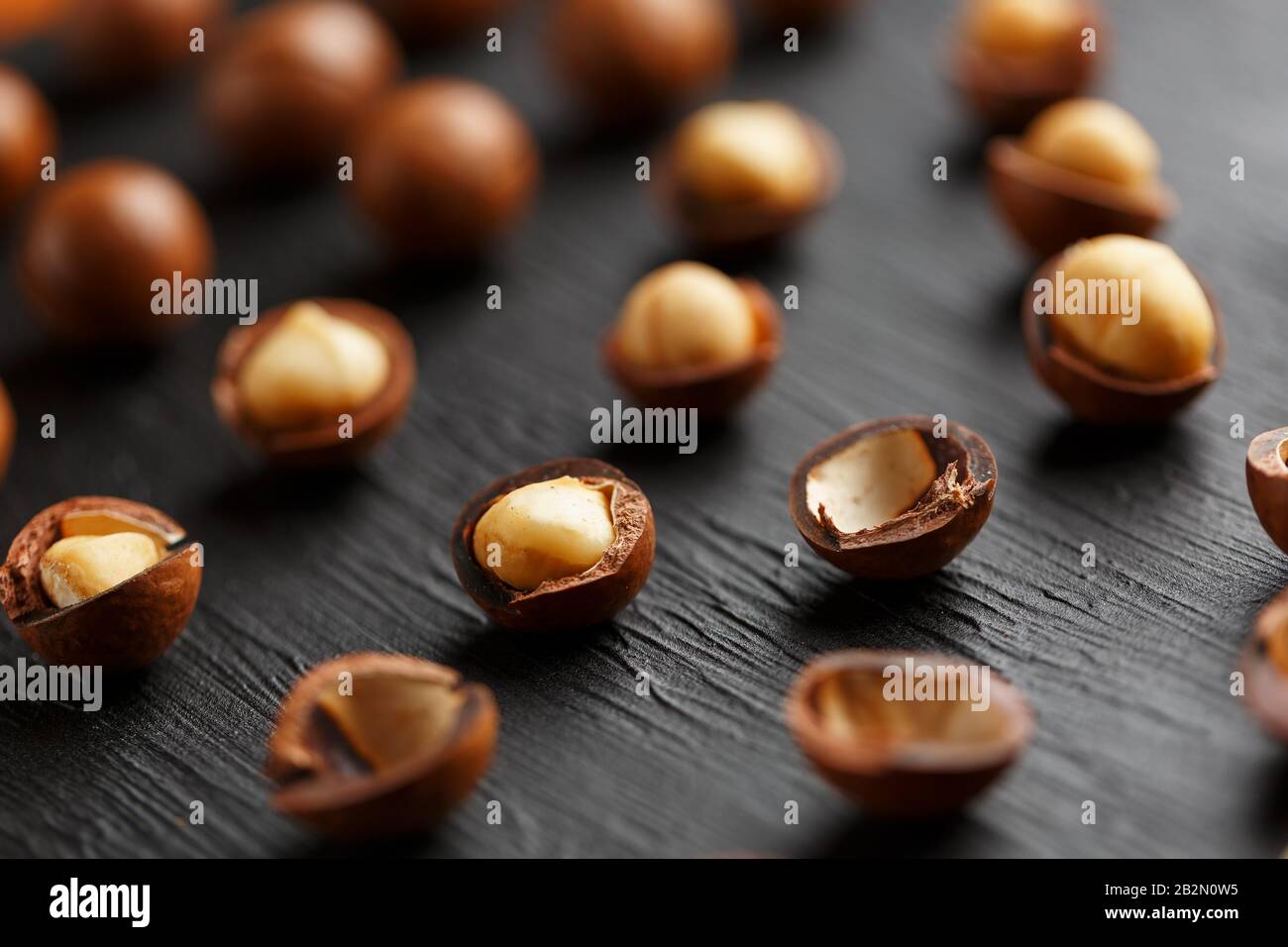 Purified and shell repeats macadamia nuts on black textural stone ...