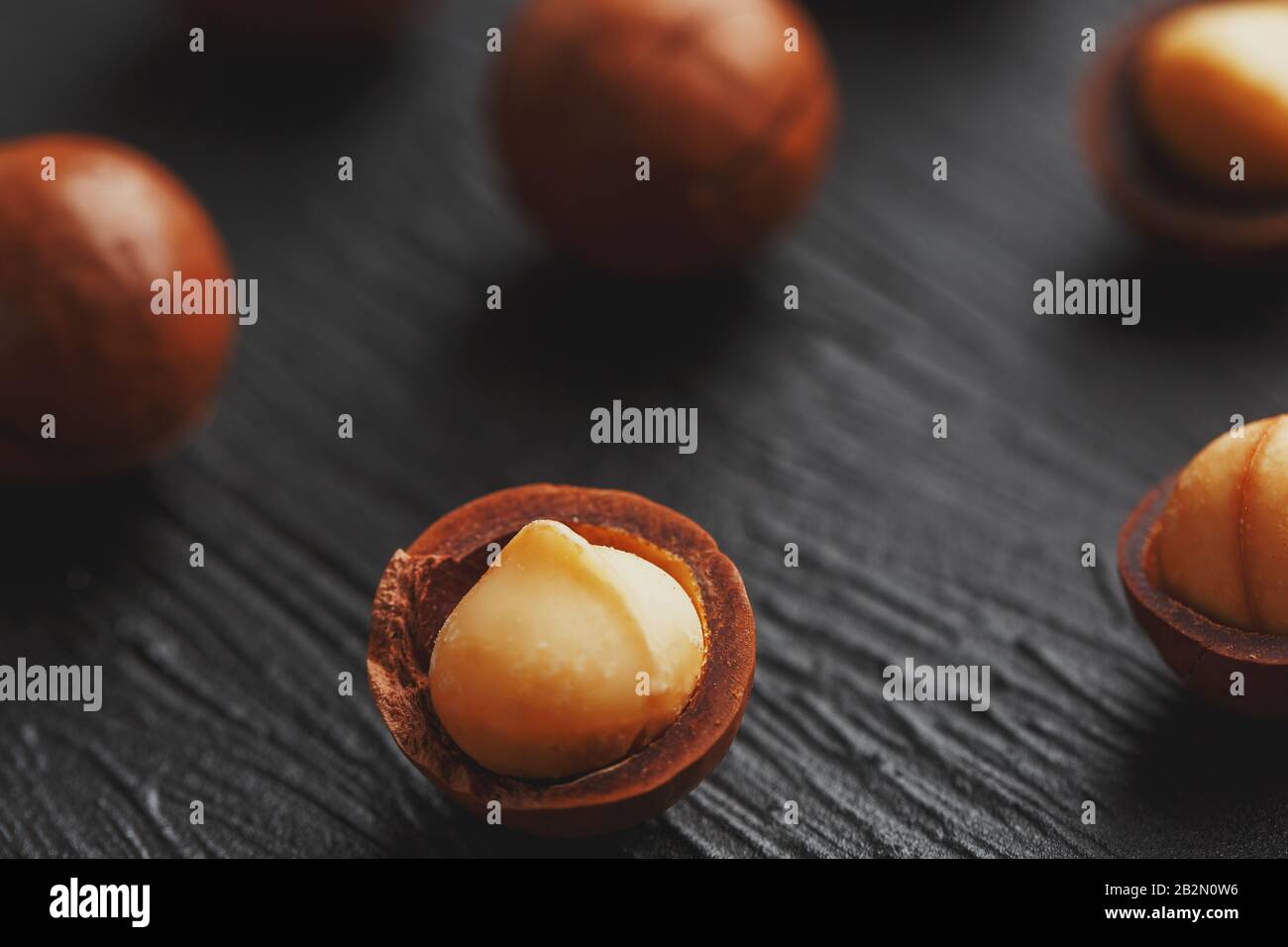 Purified and shell repeats macadamia nuts on black textural stone ...