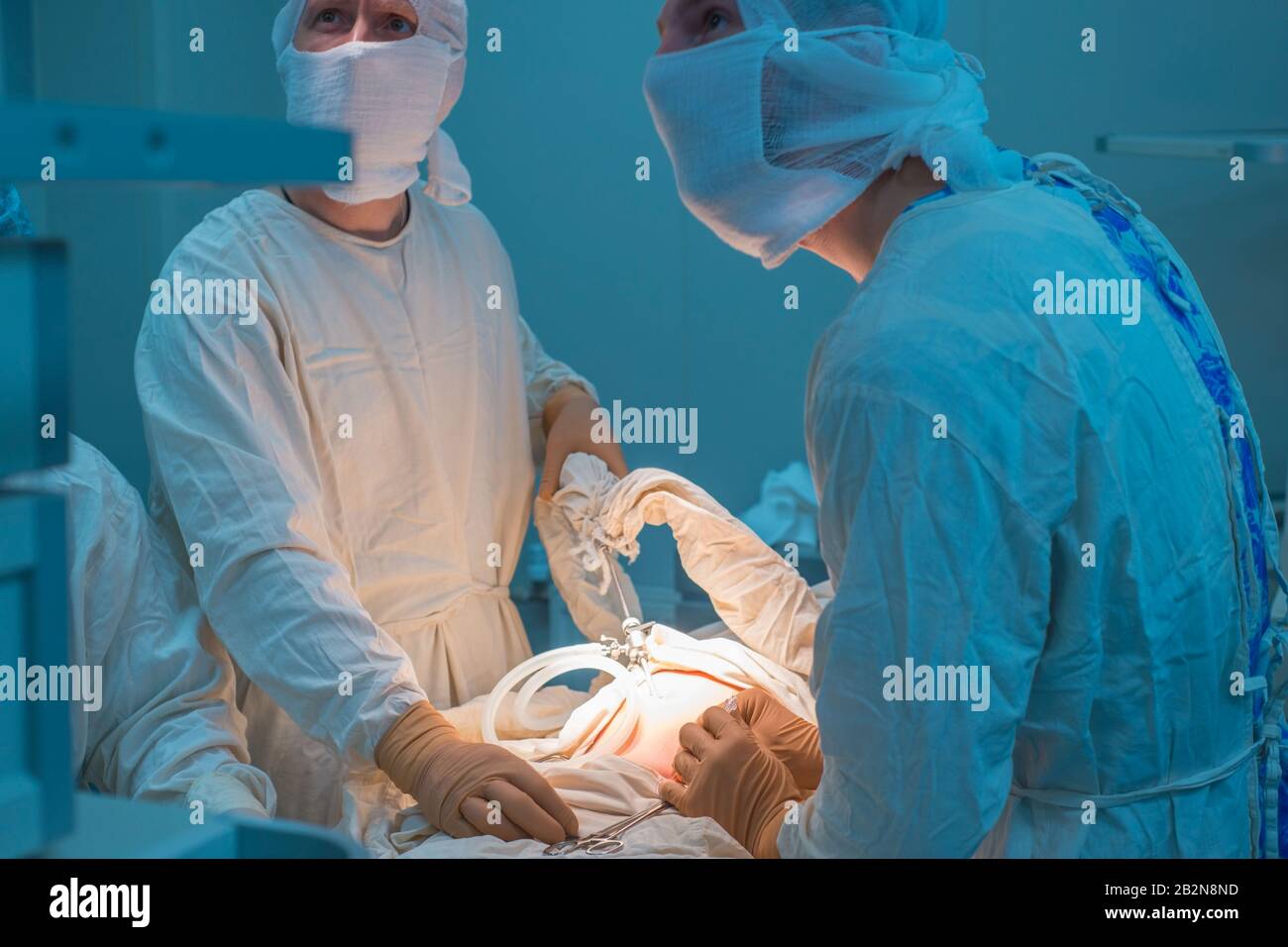close-up hands of pediatric surgeons performing surgery using laparoscopic ports for endoscopic ...