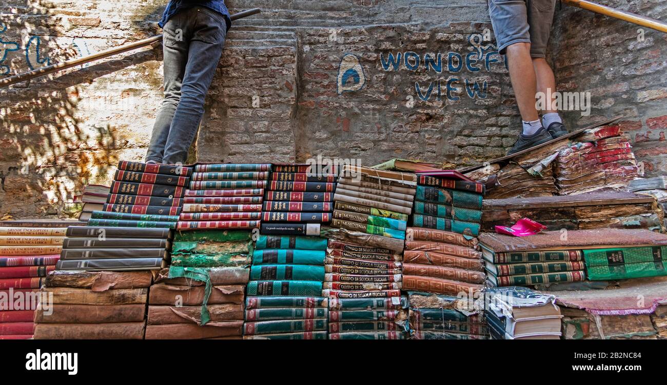 Two pairs of legs standing on piles of books in the famous library ...